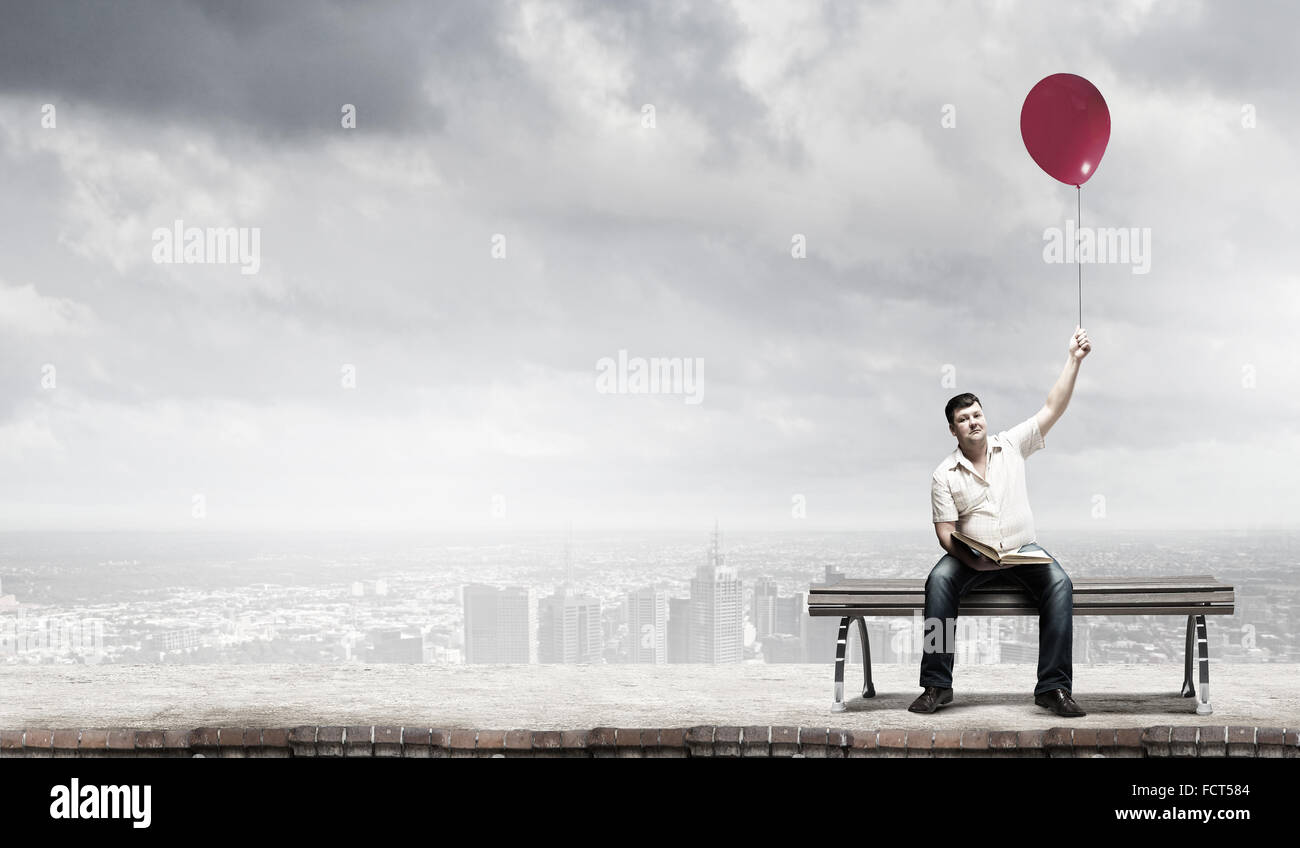 Fat man sitting on bench with book and balloon in hand Stock Photo - Alamy