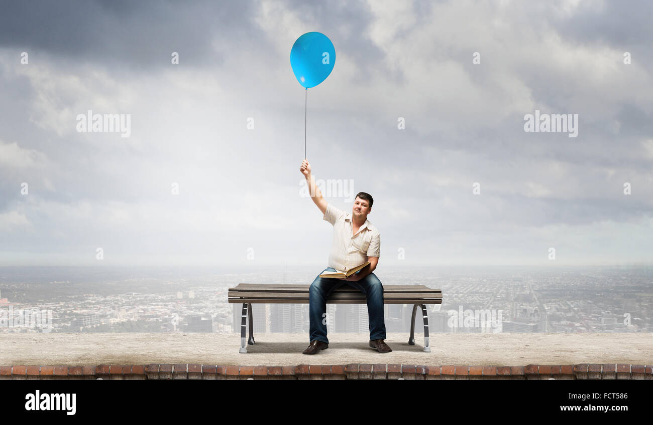 Fat man sitting on bench with book and balloon in hand Stock Photo - Alamy