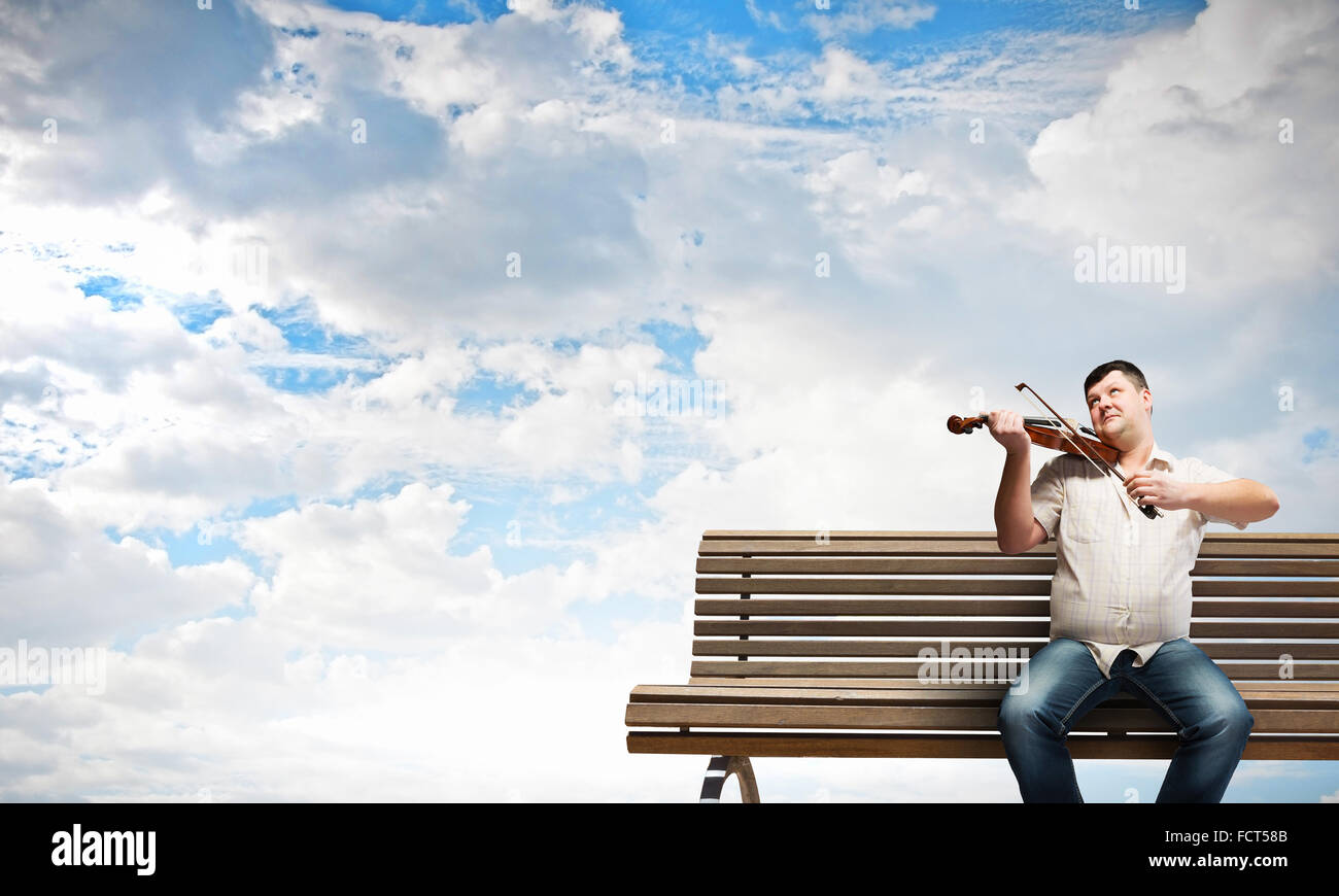 Fat man sitting on bench and playing violin Stock Photo - Alamy