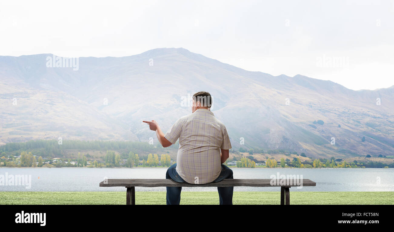 Fat man sitting on bench with his back and pointing away with finger ...