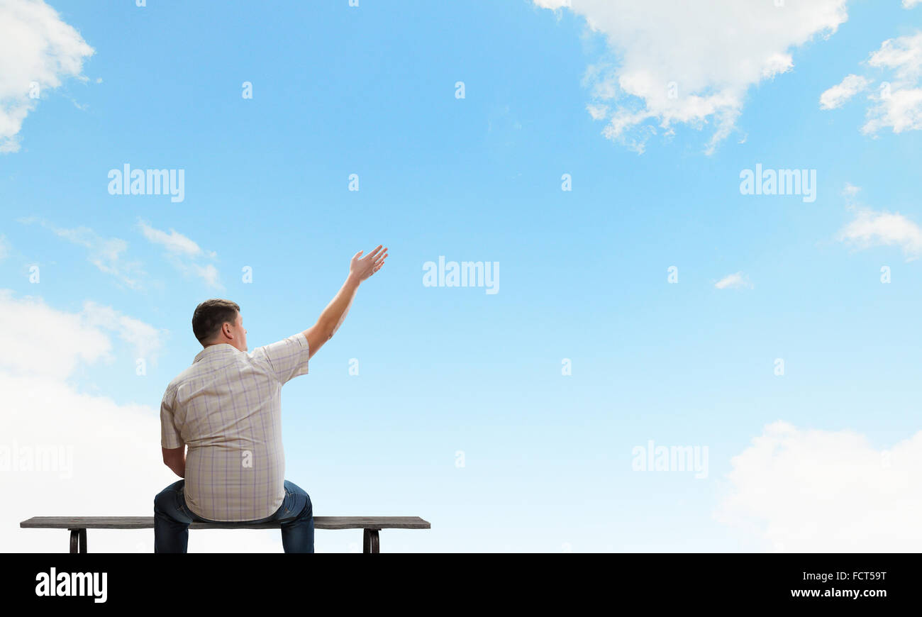 Fat man sitting on bench with his back and pointing away Stock Photo ...