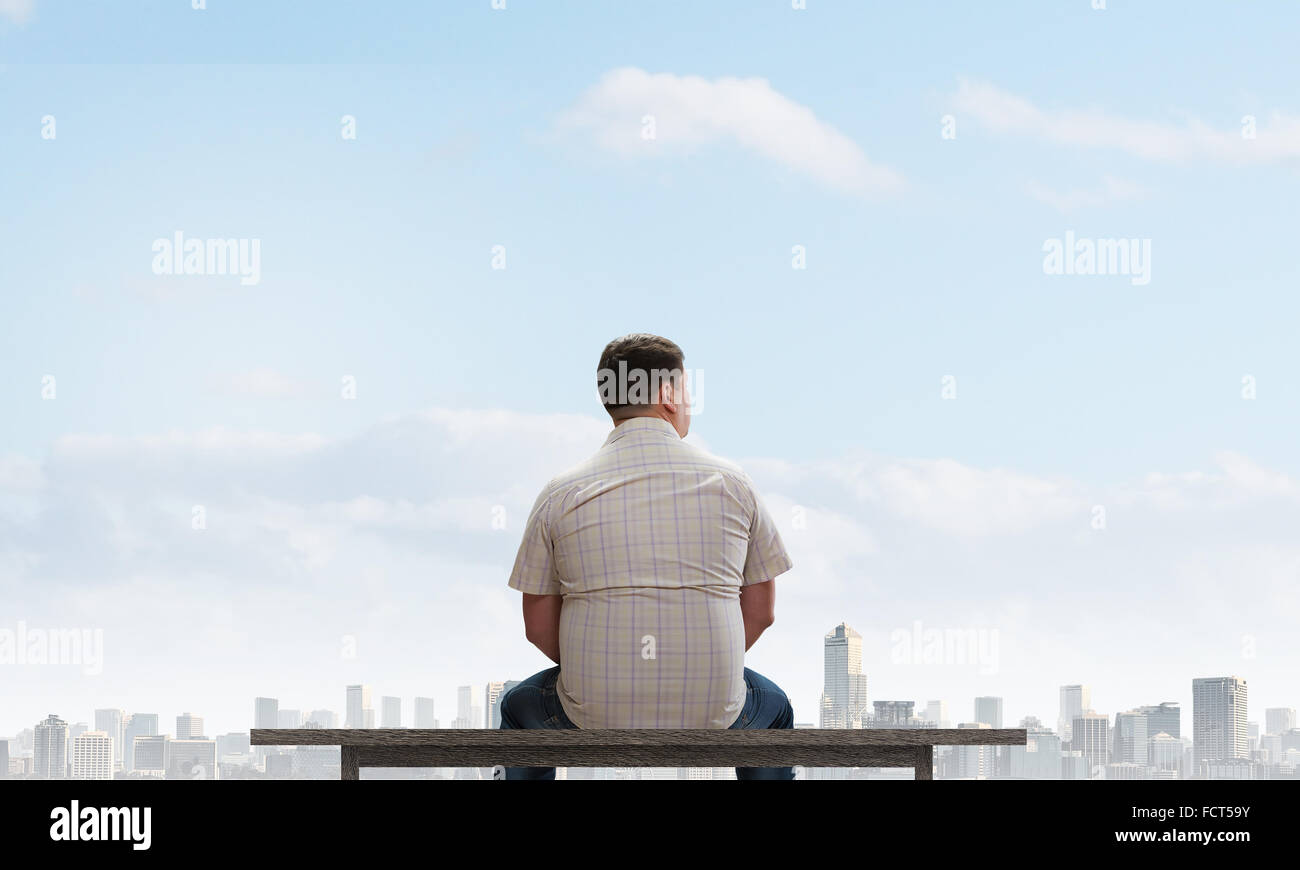 Fat man sitting on bench with his back and looking away Stock Photo - Alamy