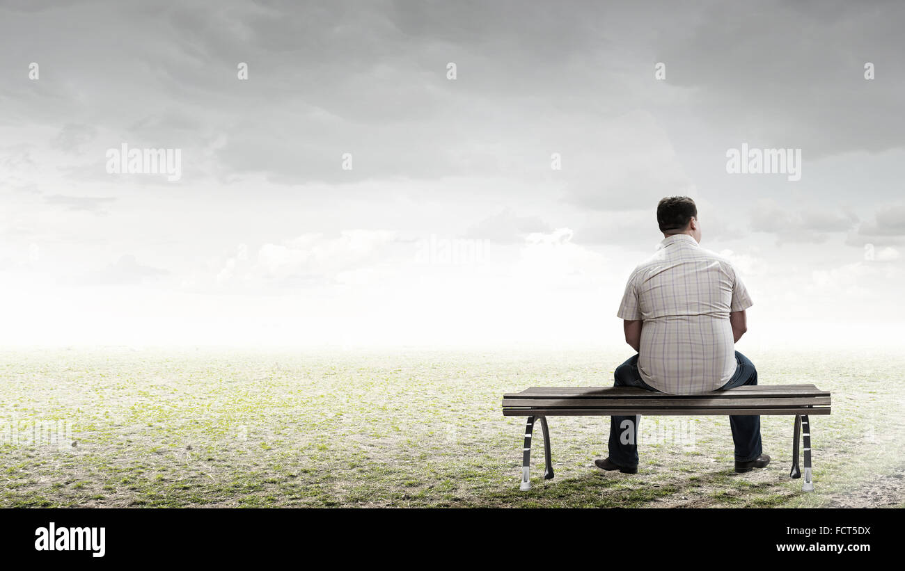 Fat man sitting on bench with his back and looking away Stock Photo - Alamy