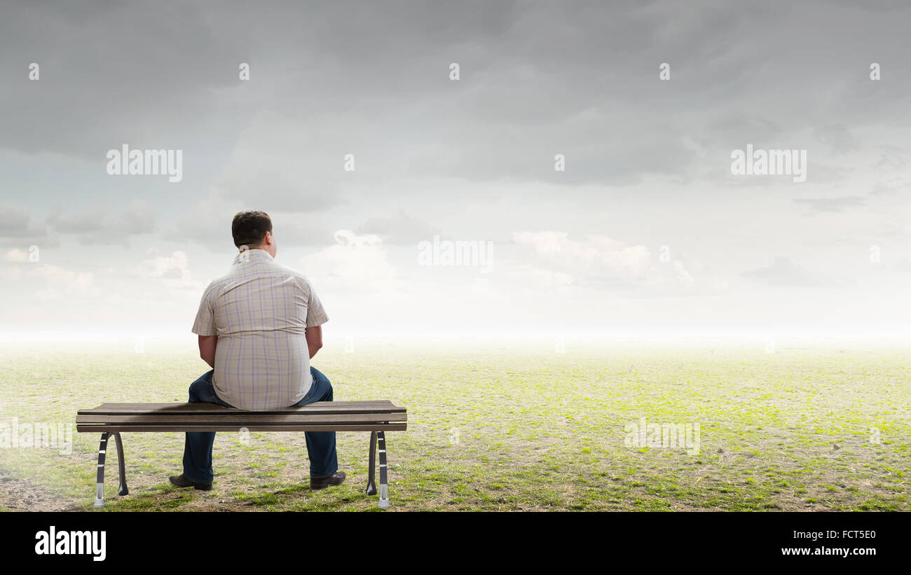 Fat man sitting on bench with his back and looking away Stock Photo - Alamy