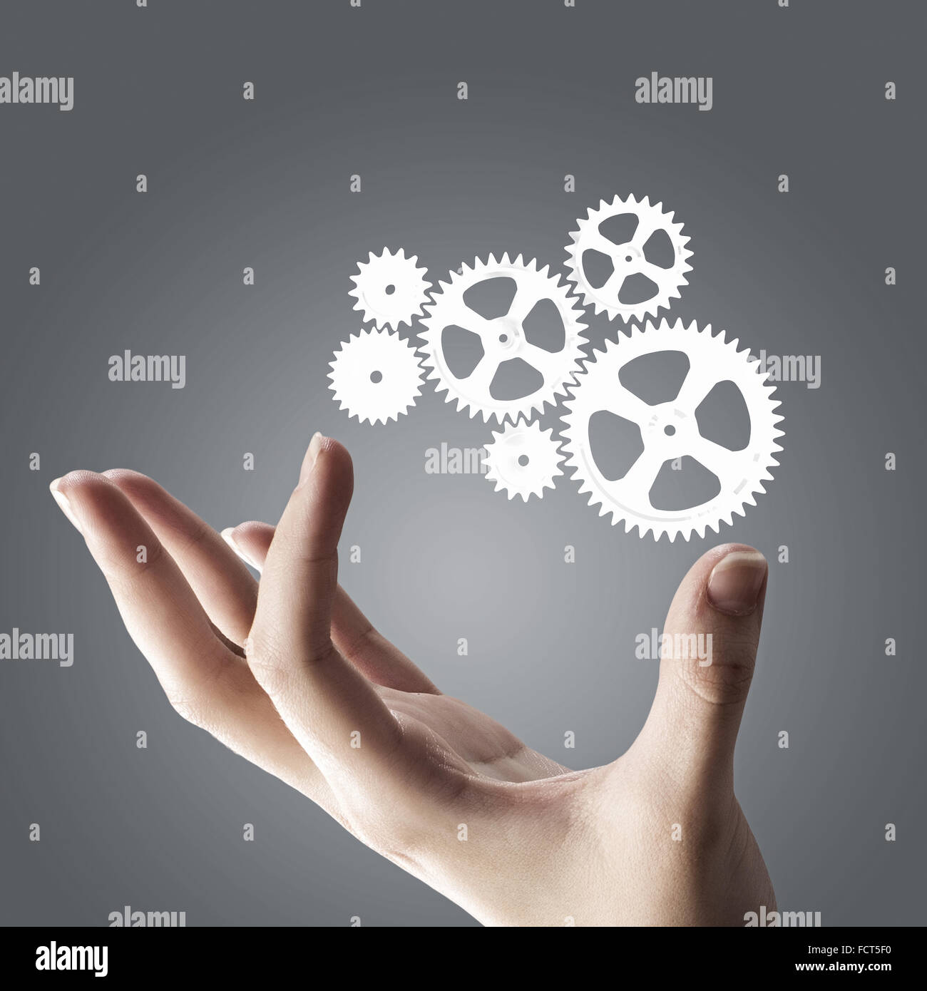 Close up of hand and gears mechanism on gray background Stock Photo - Alamy