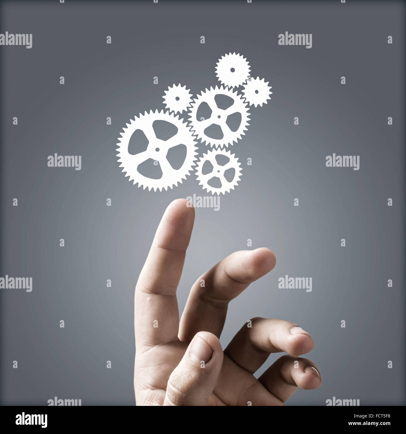 Close up of hand and gears mechanism on gray background Stock Photo - Alamy