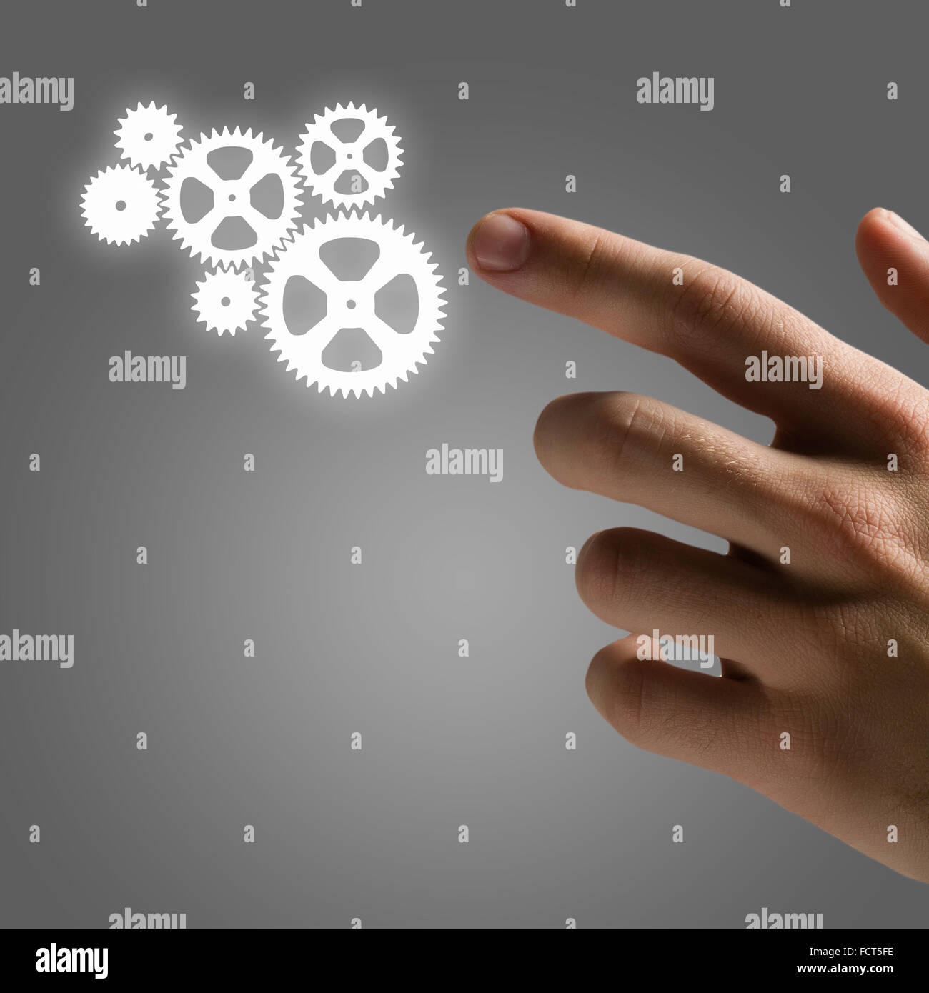 Close up of hand and gears mechanism on gray background Stock Photo - Alamy