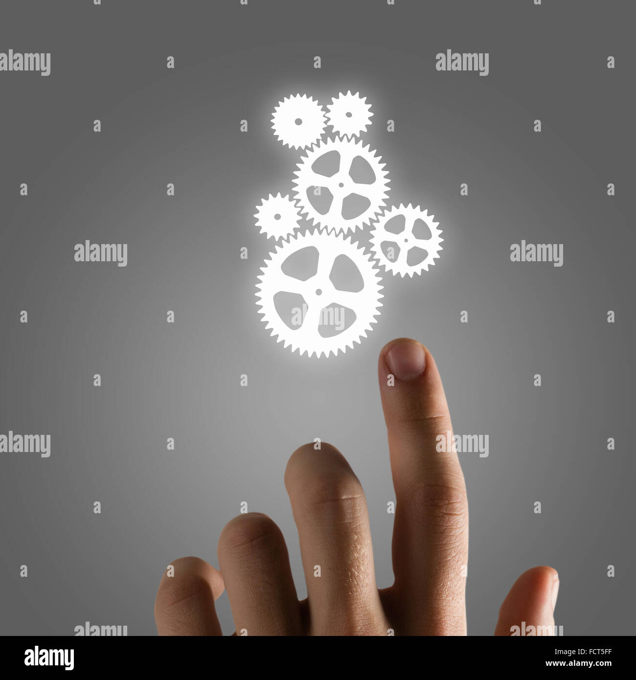 Close up of hand and gears mechanism on gray background Stock Photo - Alamy