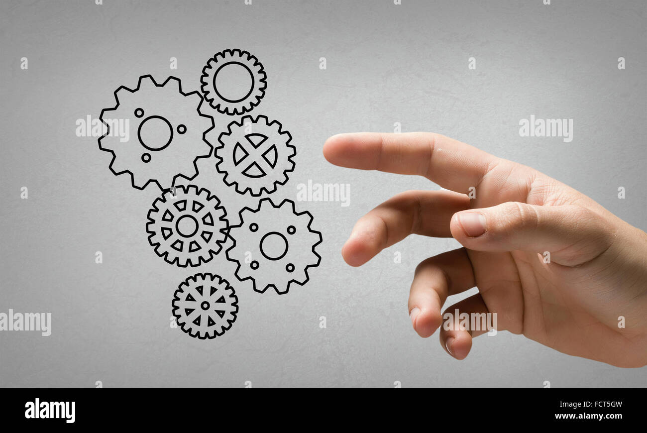Close up of hand and gears mechanism on gray background Stock Photo - Alamy
