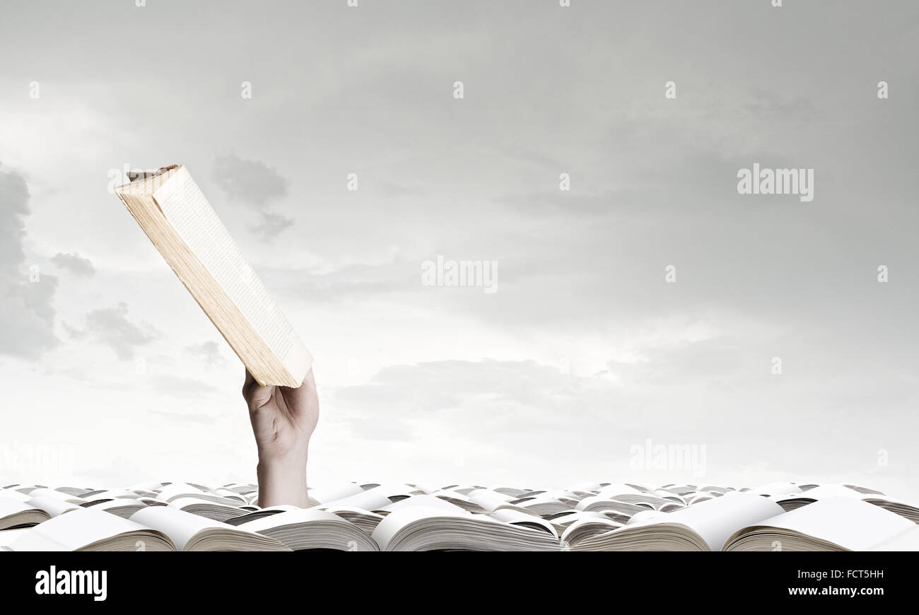 Hand with book reaching out from pile of old books Stock Photo - Alamy