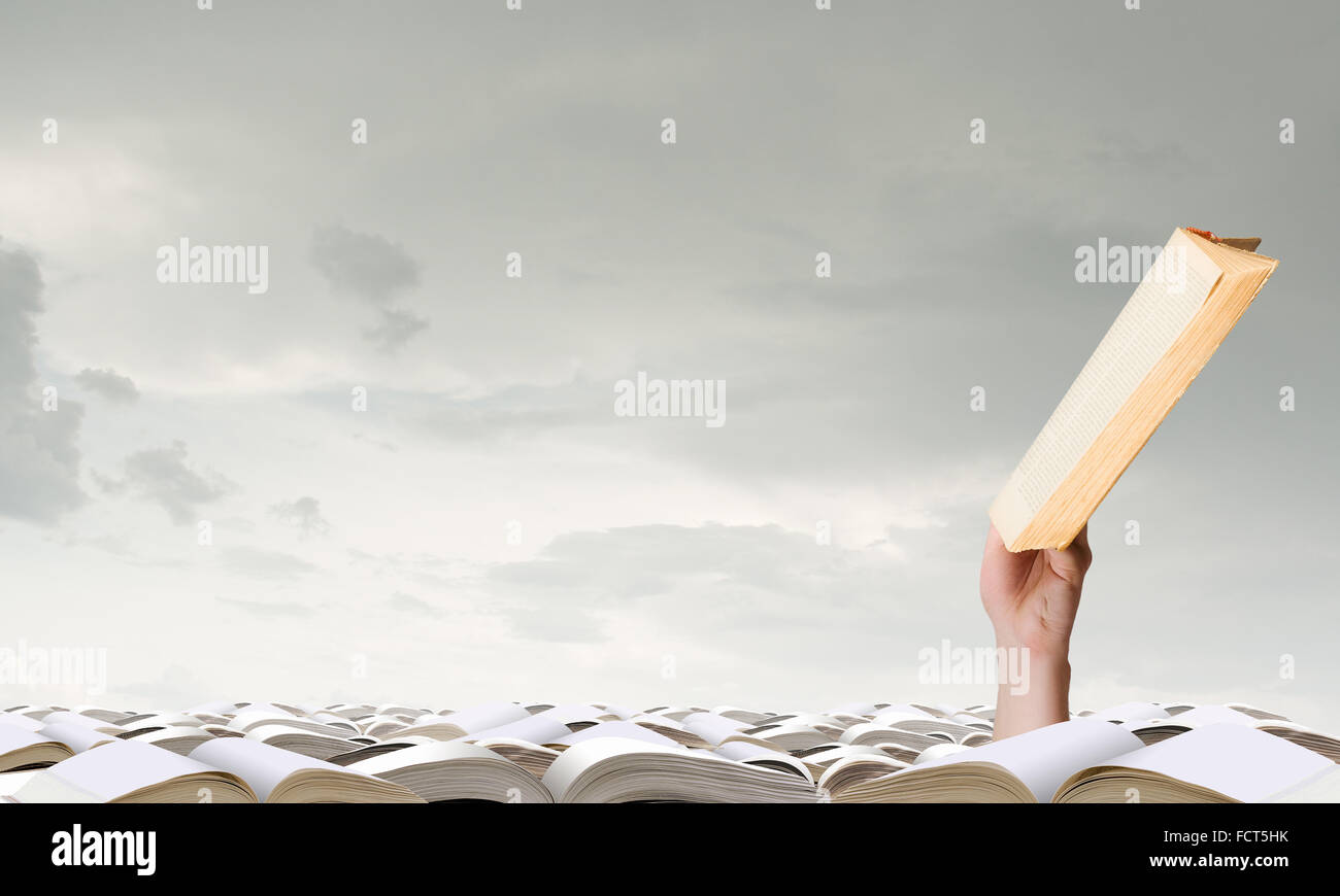 Hand with book reaching out from pile of old books Stock Photo - Alamy