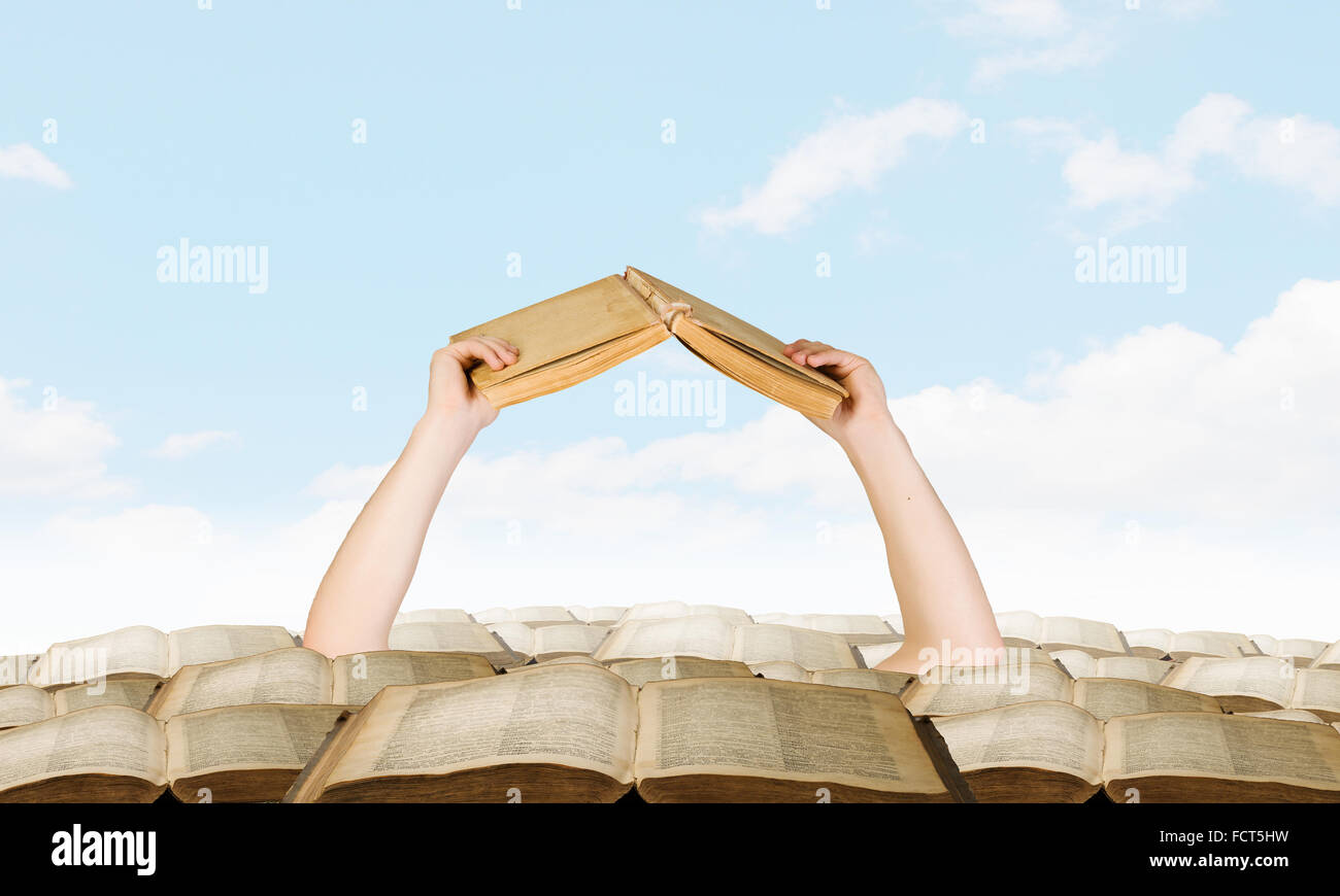 Hand with book reaching out from pile of old books Stock Photo - Alamy