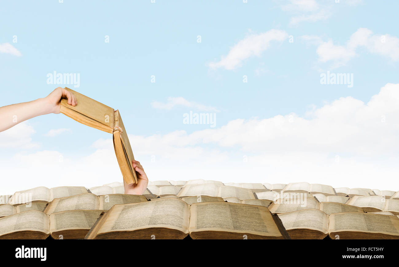 Hand with book reaching out from pile of old books Stock Photo - Alamy