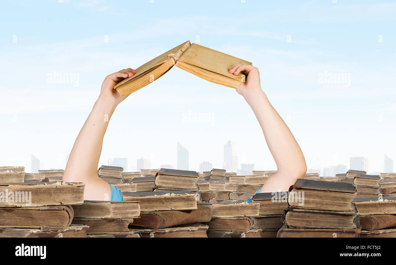 Hand with book reaching out from pile of old books Stock Photo - Alamy