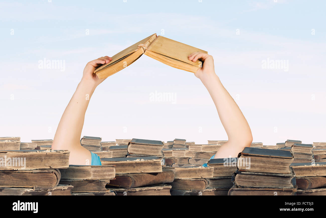 Hand with book reaching out from pile of old books Stock Photo - Alamy