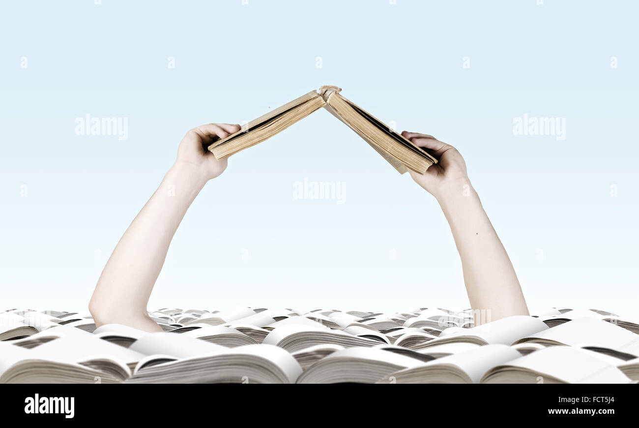 Hand with book reaching out from pile of old books Stock Photo - Alamy