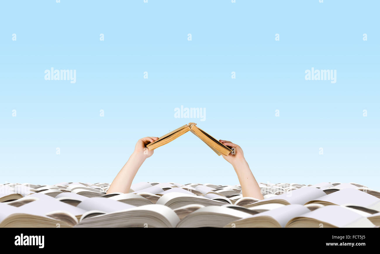 Hand with book reaching out from pile of old books Stock Photo - Alamy