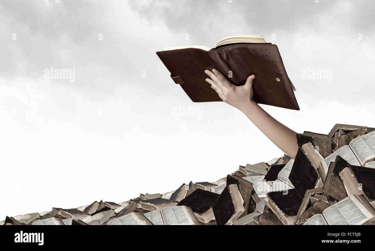 Hand with book reaching out from pile of old books Stock Photo - Alamy