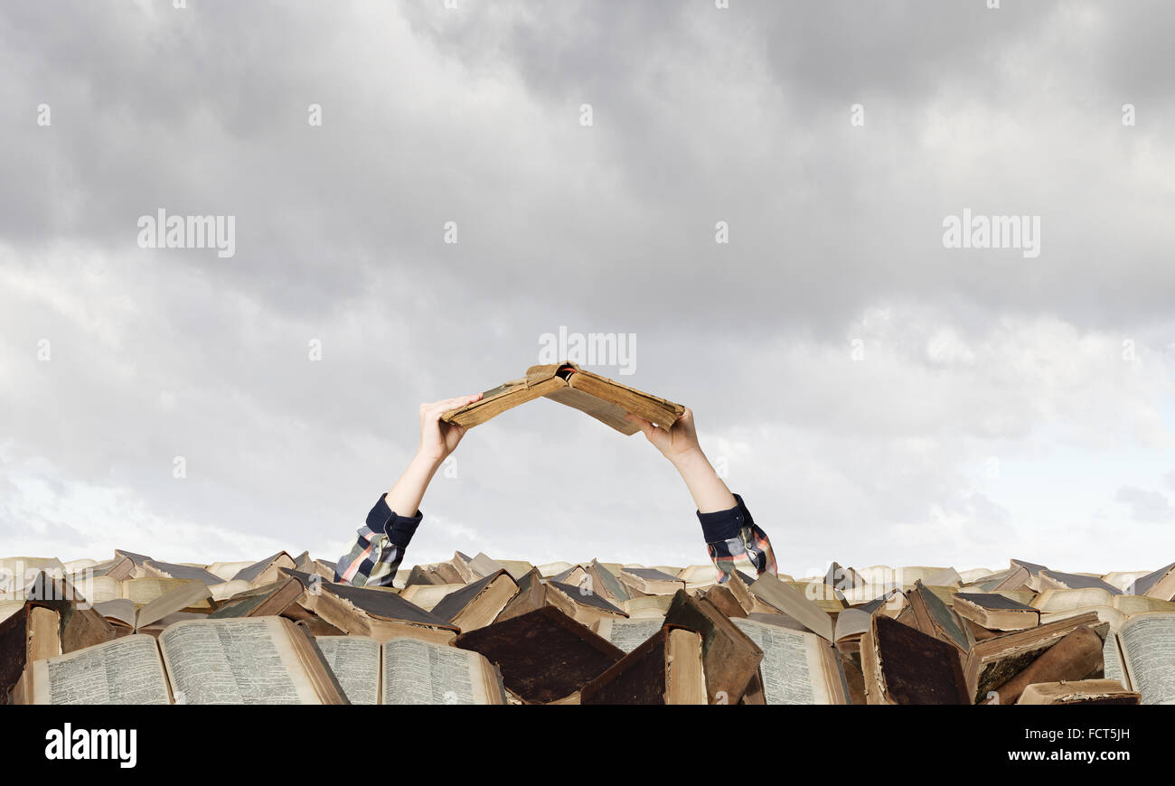 Hand with book reaching out from pile of old books Stock Photo - Alamy