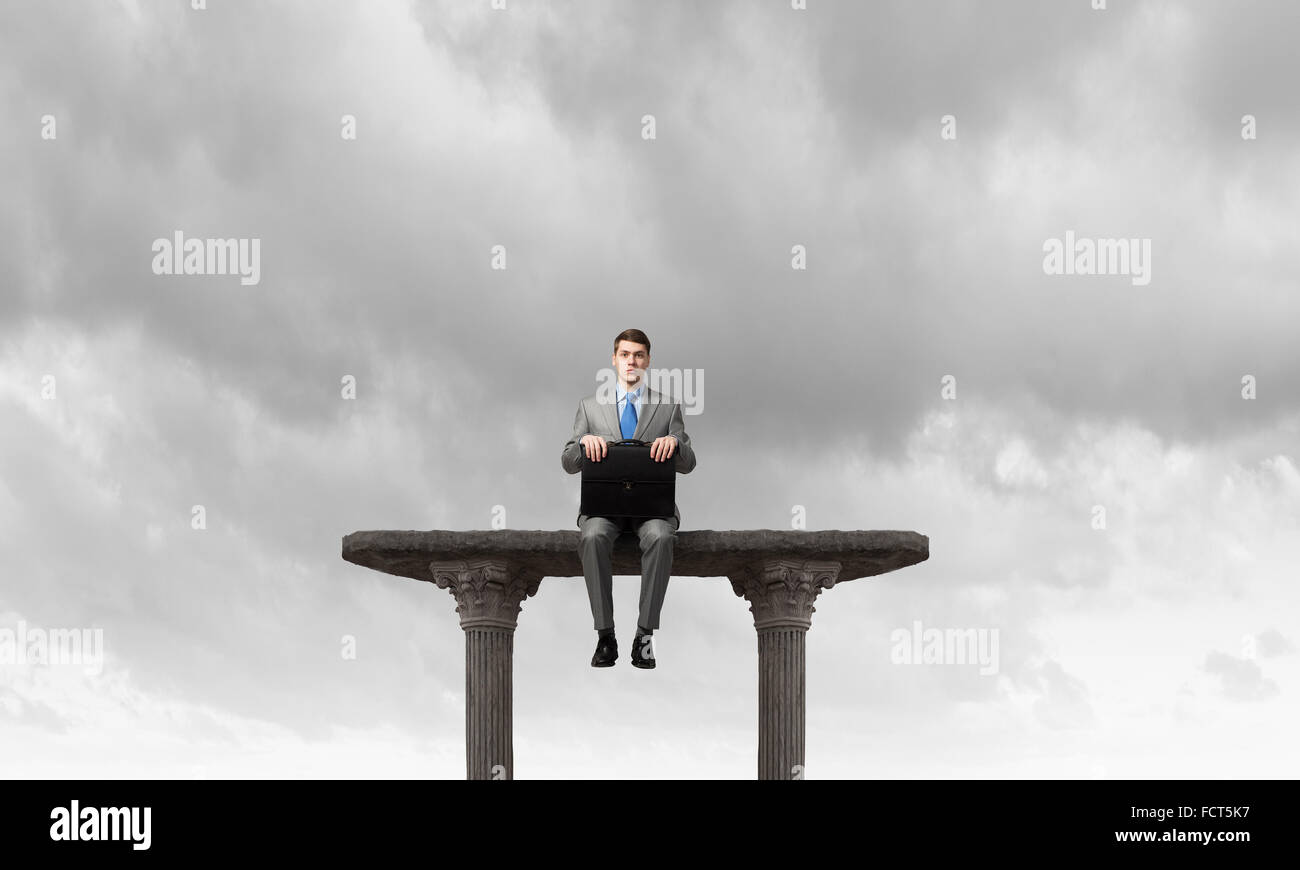 Young businessman with briefcase sitting on top of building Stock Photo ...