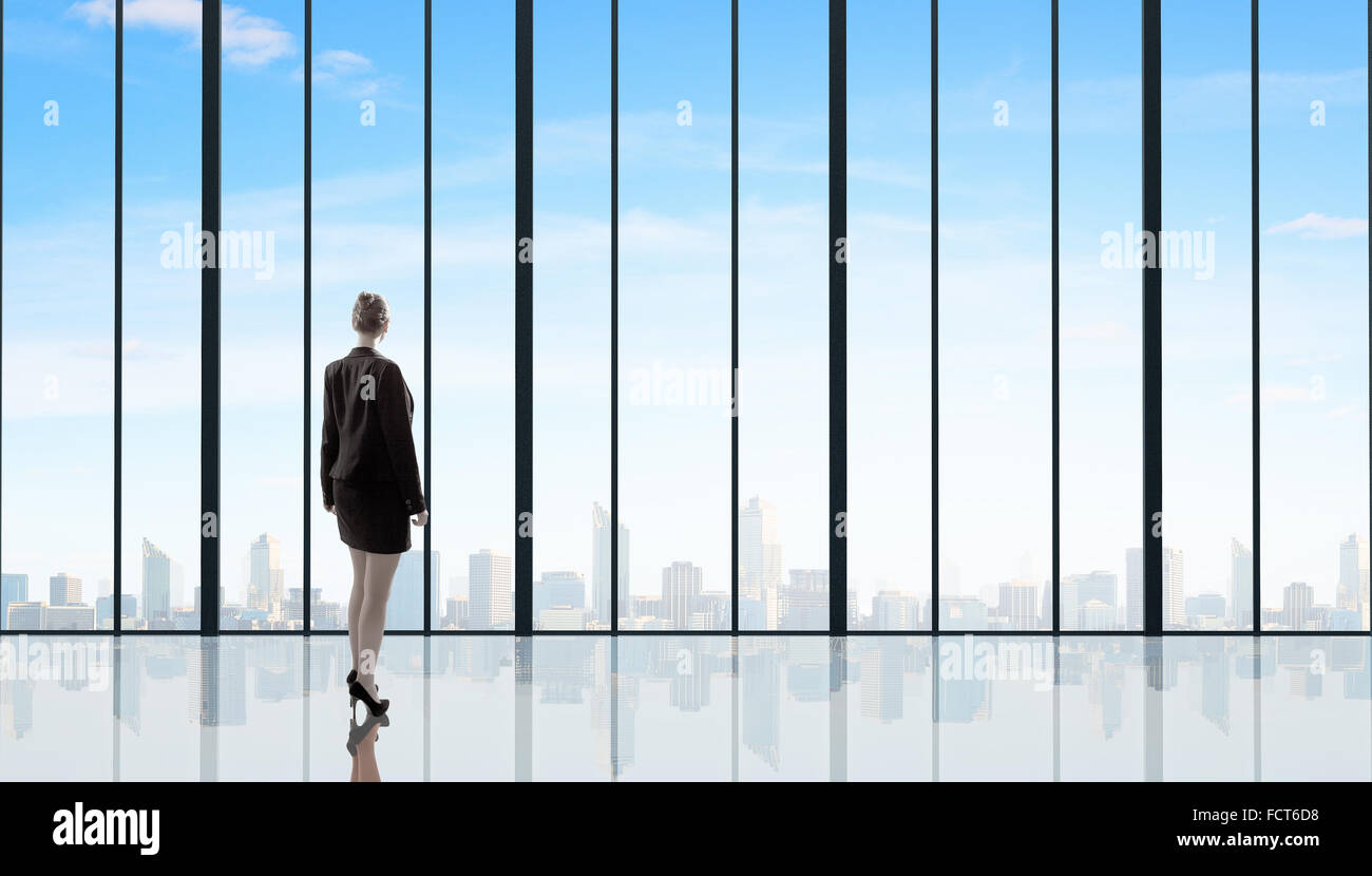 Businesswoman standing with back and looking in office window Stock ...