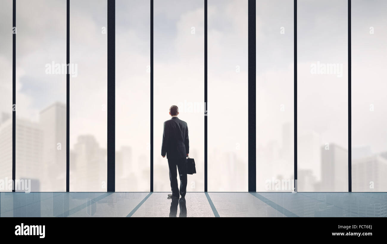 Businessman standing with back and looking in office window Stock Photo ...