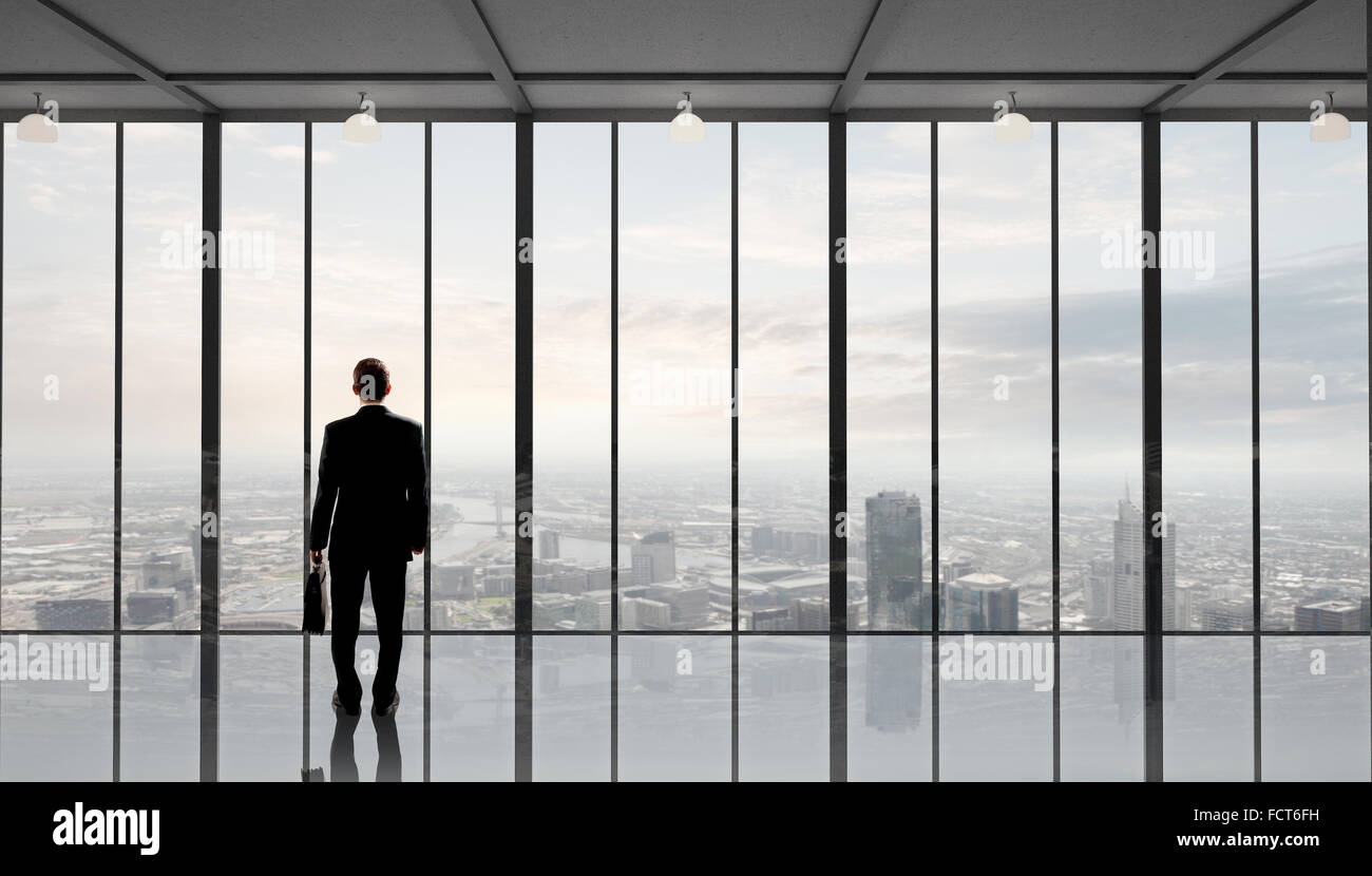 Businessman standing with back and looking in office window Stock Photo ...