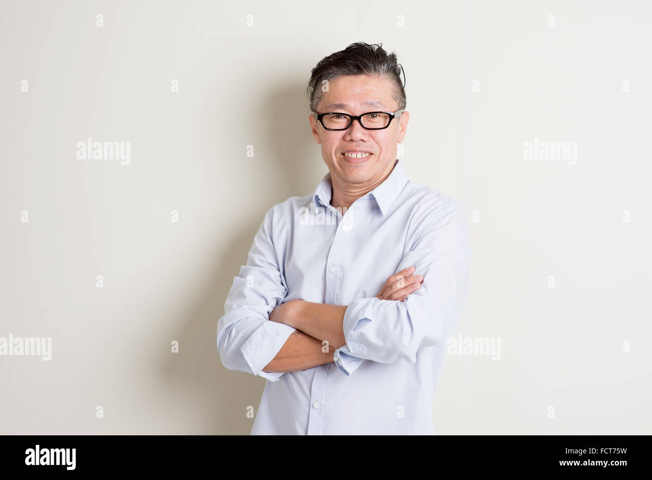 Portrait of happy single mature 50s Asian man in casual business arms ...