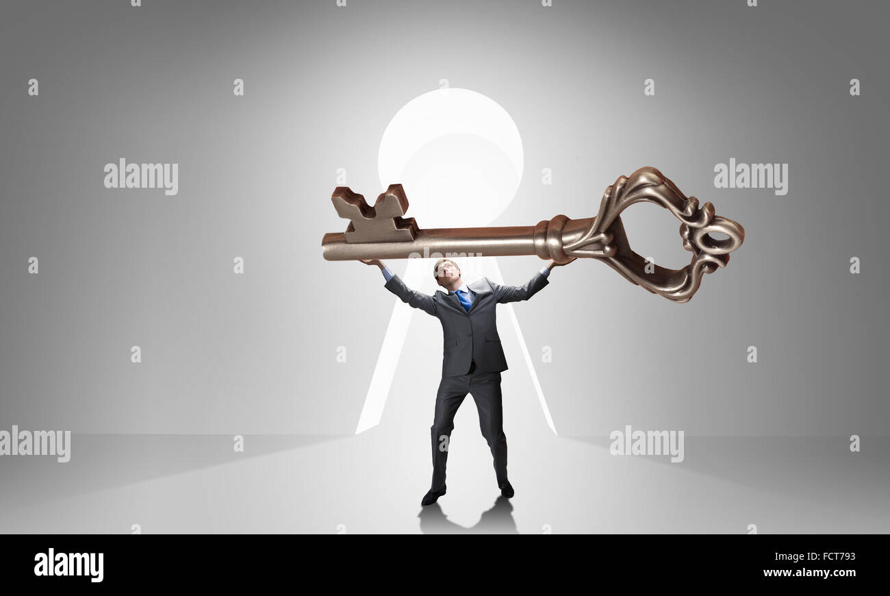 Young businessman and lifting big key above head Stock Photo - Alamy