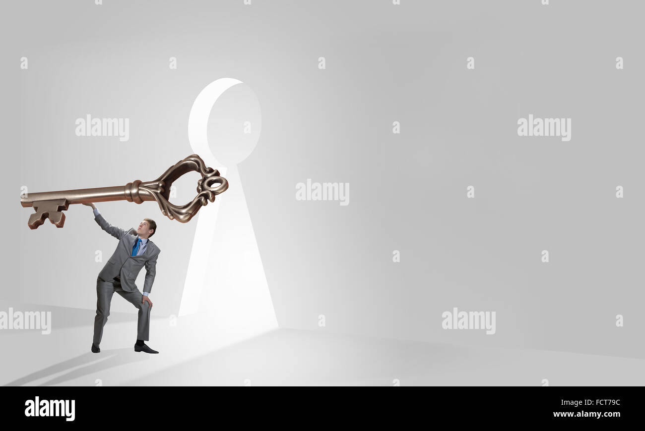 Young businessman and lifting big key above head Stock Photo - Alamy