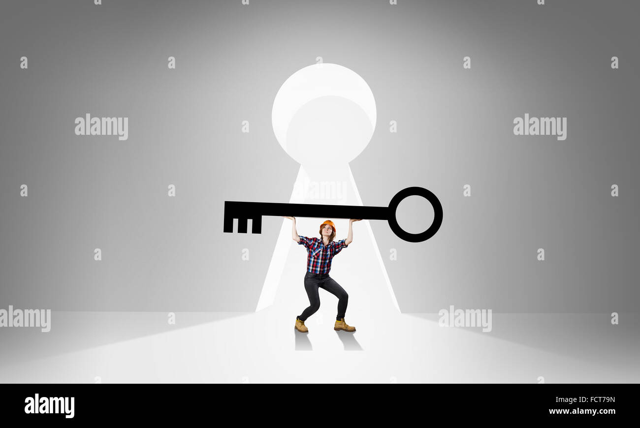 Young engineer woman lifting big key above head Stock Photo - Alamy