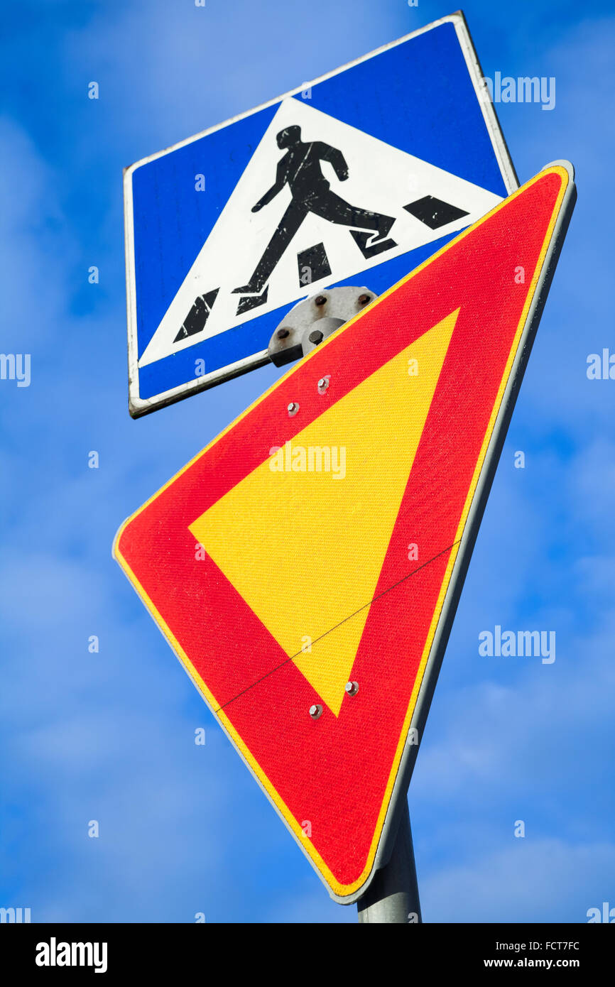 Pedestrian crossing and give way. Two road signs above blue sky background in Finland Stock ...
