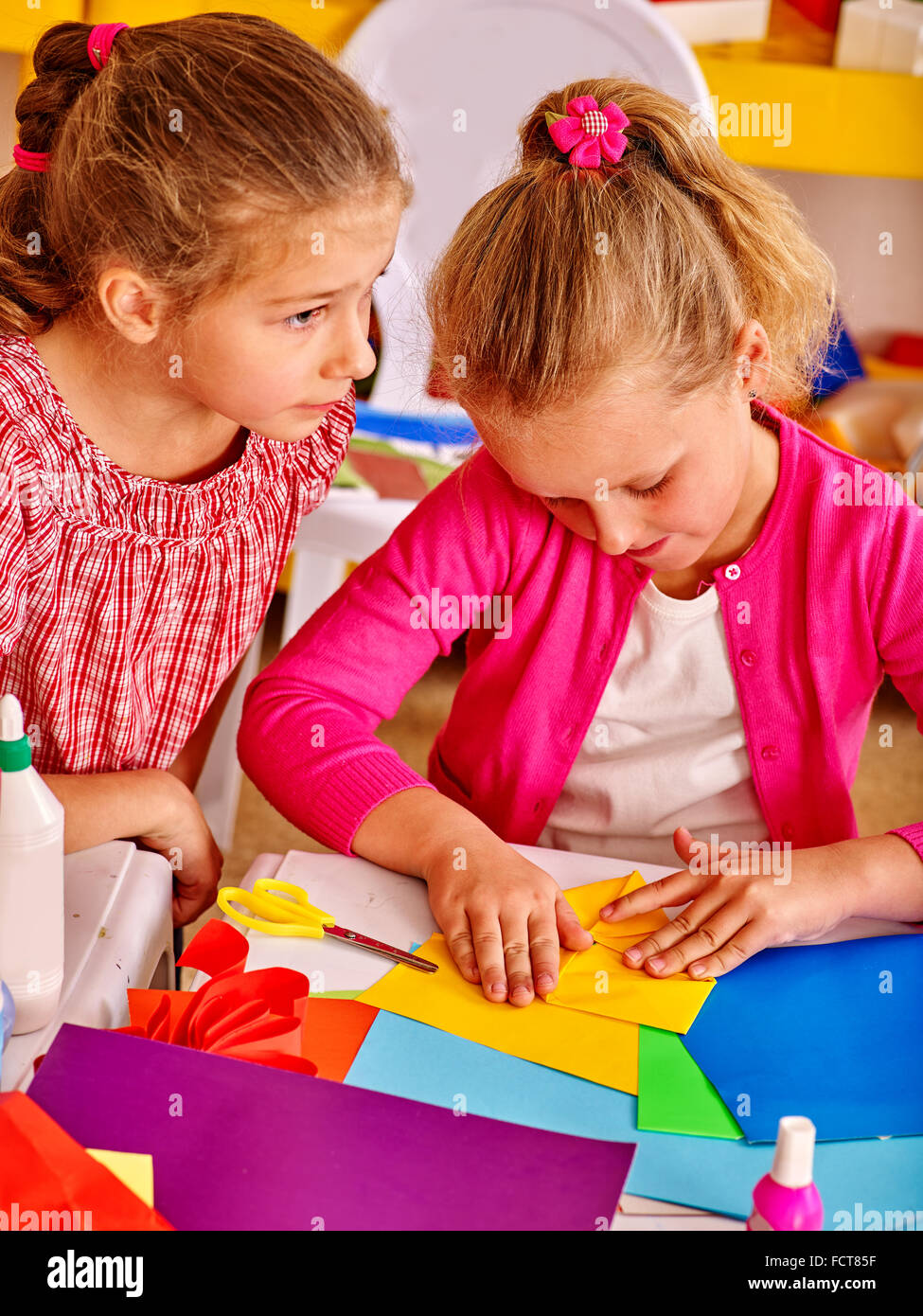Kids holding colored paper on table in kindergarten Stock Photo - Alamy
