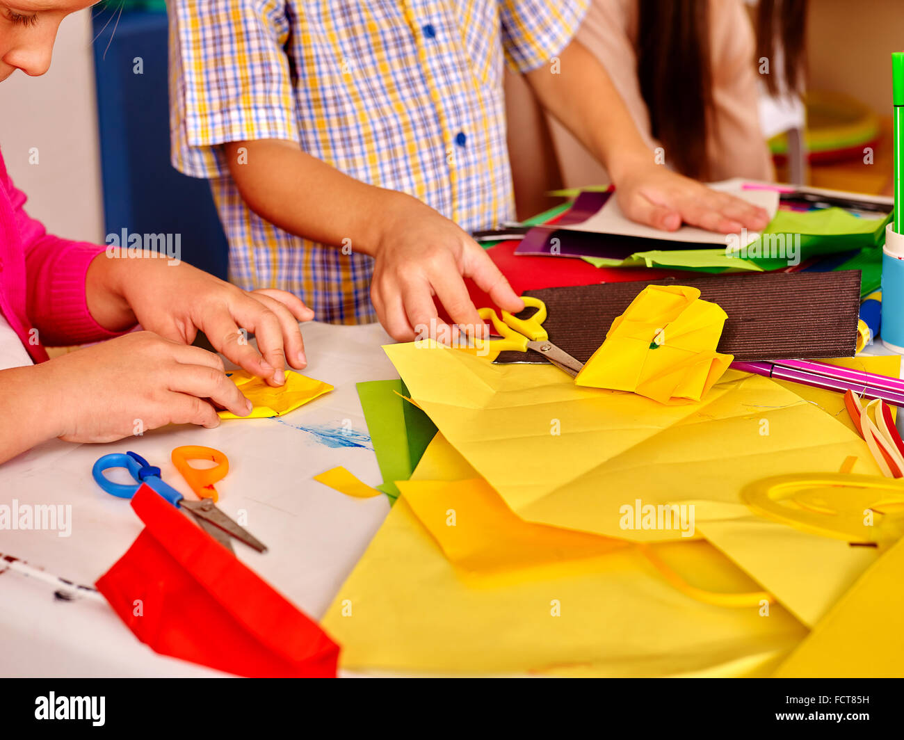 Kids holding colored paper on table in kindergarten Stock Photo - Alamy