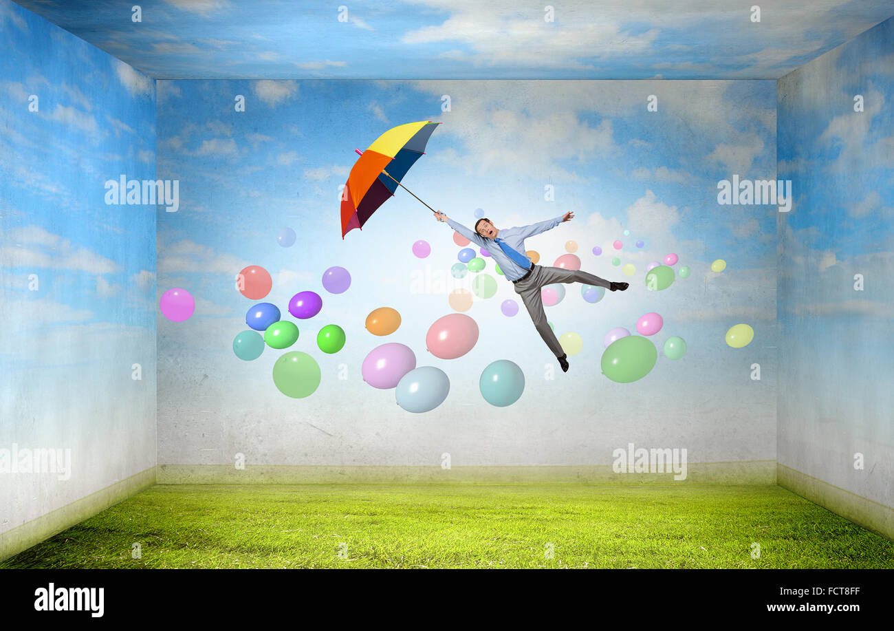 Young businessman flying high in sky on umbrella Stock Photo - Alamy