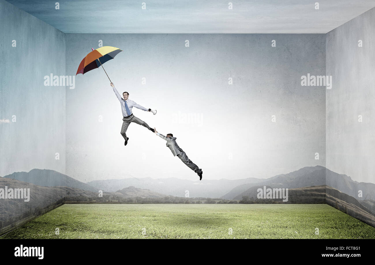 Man trying to catch another who flying on colorful umbrella Stock Photo ...
