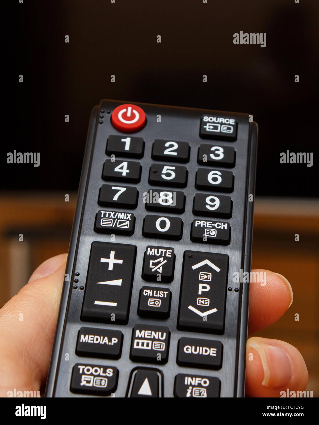 Hand holding infrared remote control for television and TV screen in ...
