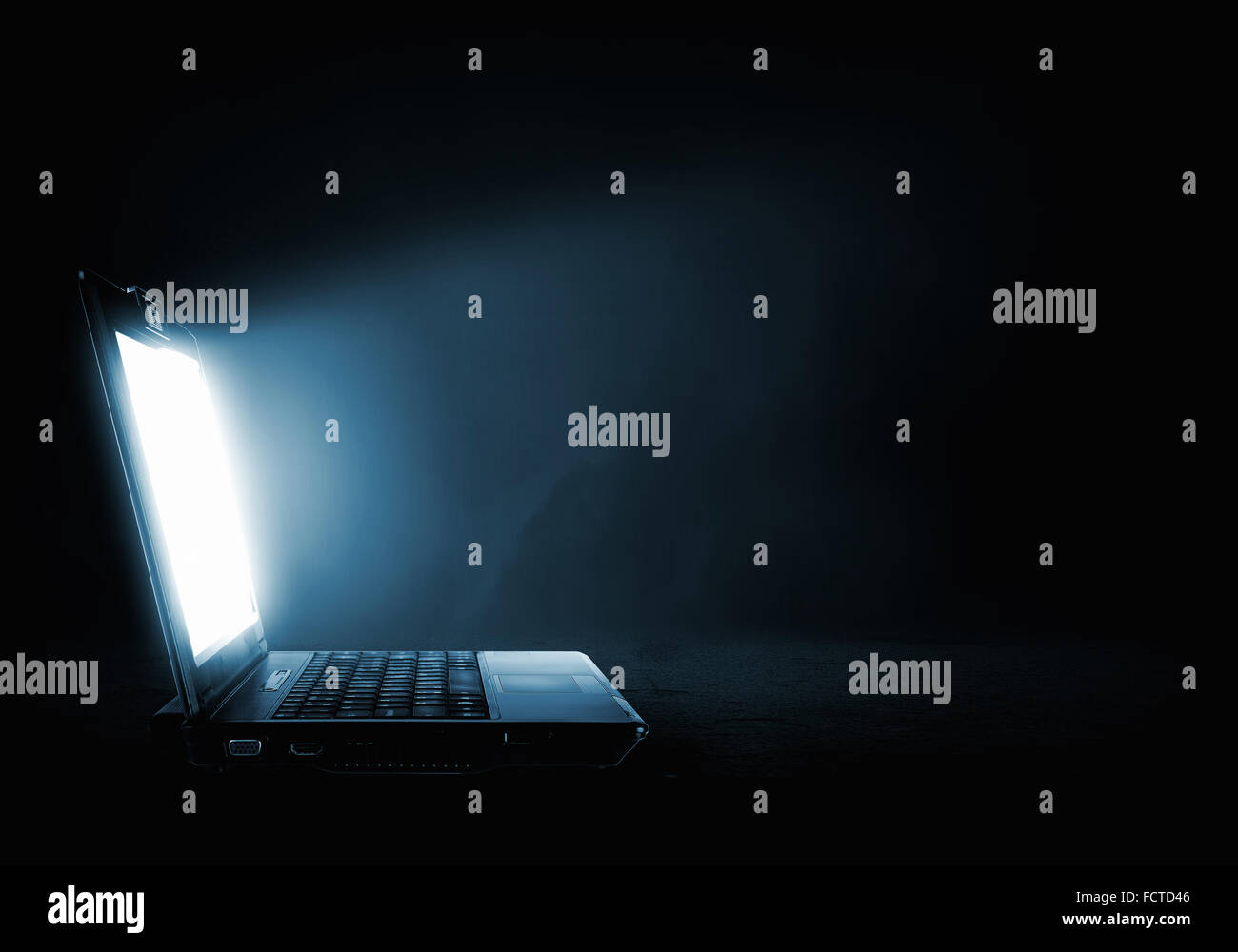 Open laptop with light coming from screen on dark background Stock ...