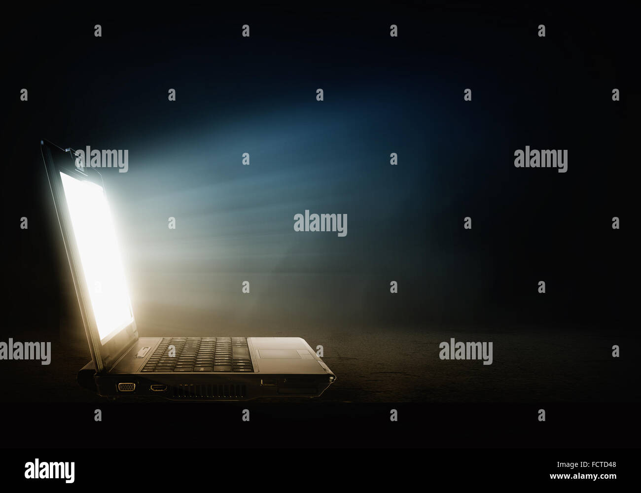 Open laptop with light coming from screen on dark background Stock ...