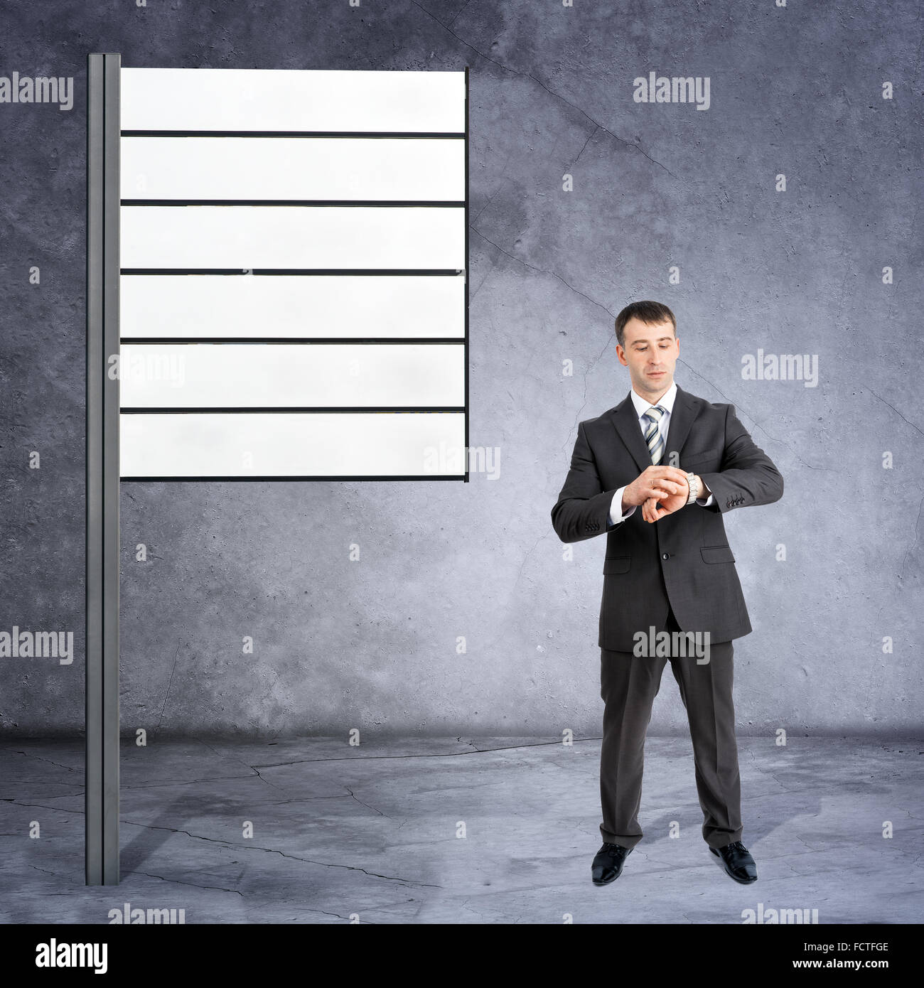Businessman looking at his hand near road sign Stock Photo - Alamy