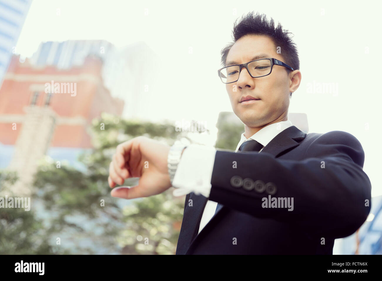 Businessman standing in street and looking at his watch Stock Photo - Alamy