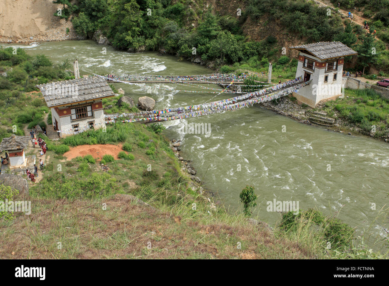 A wire suspension bridge crosses a river in Bhutan, on the route ...