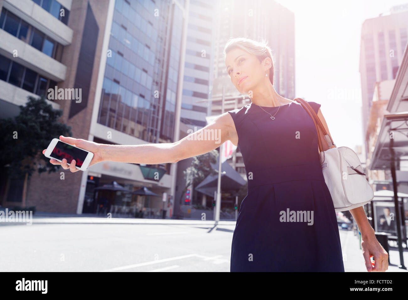 Businesswoman in a city street waving for taxi Stock Photo - Alamy