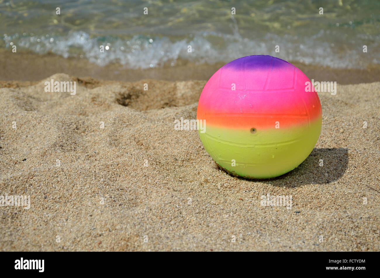 Colorful beach ball on sandy beach with wave behind Stock Photo - Alamy