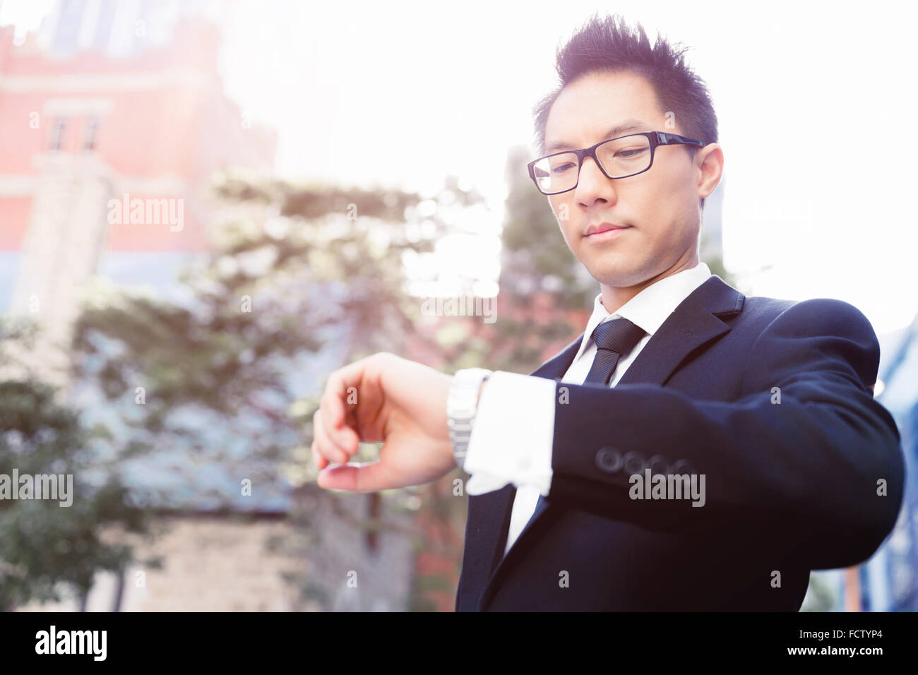 Businessman standing in street and looking at his watch Stock Photo - Alamy
