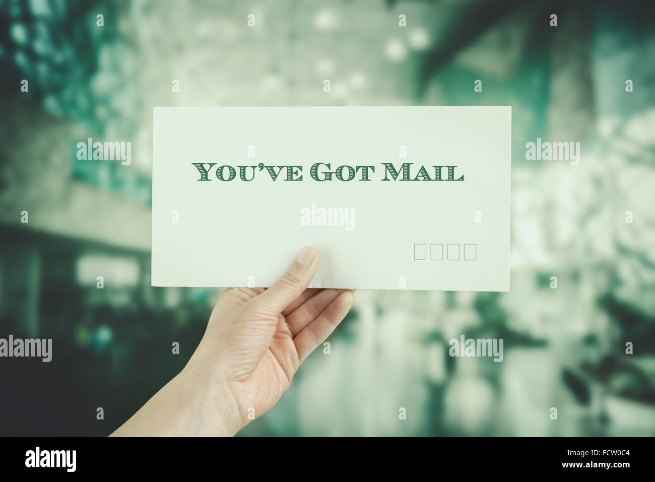 Female hand delivering a postage envelope on blurred urban background ...