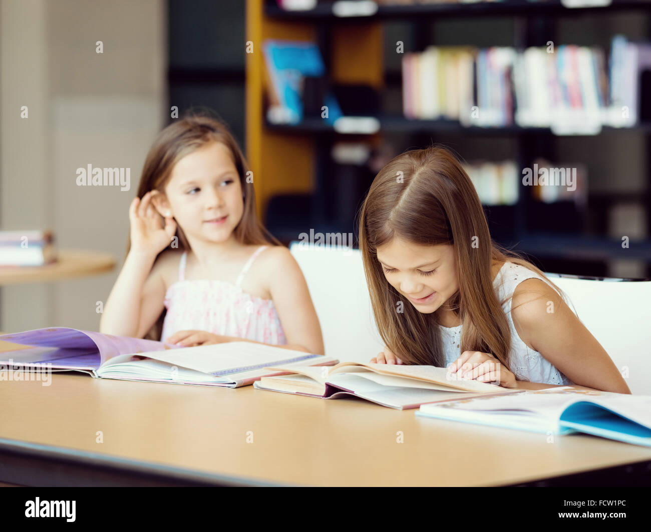 Little girls reading books in library Stock Photo - Alamy