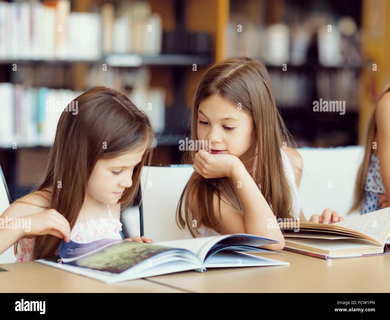 Little girls reading books in library Stock Photo - Alamy