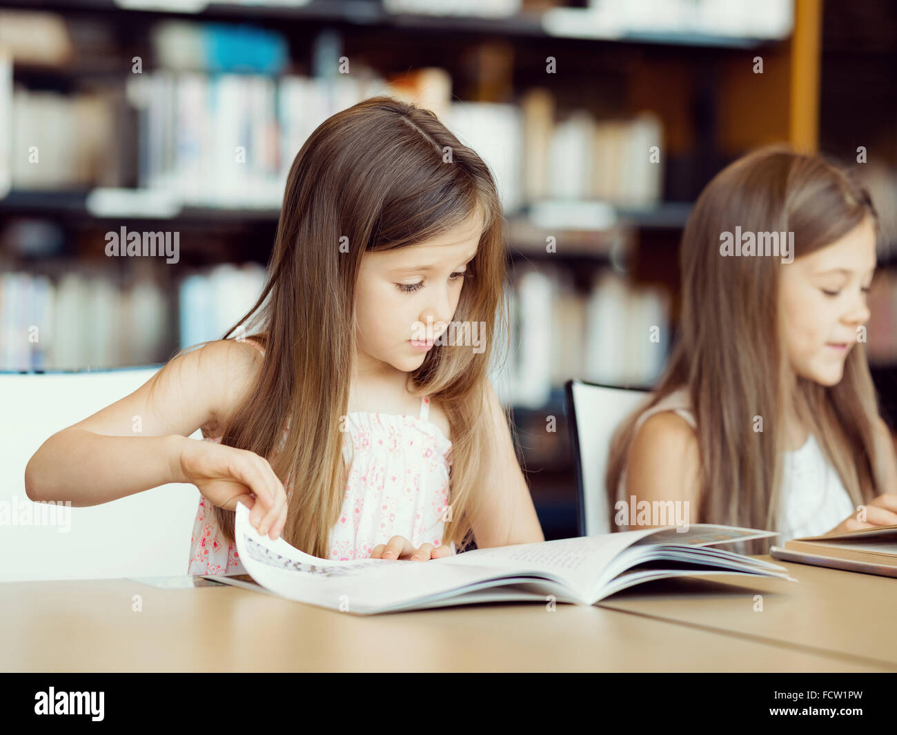 Little girls reading books in library Stock Photo - Alamy
