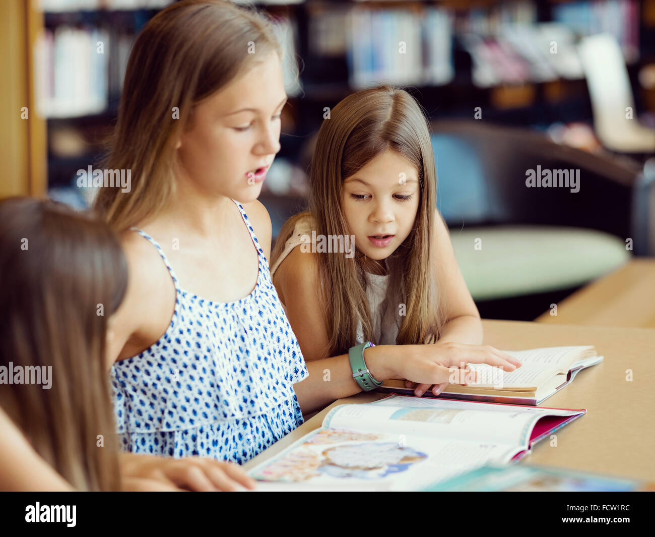 Little girls reading books in library Stock Photo - Alamy